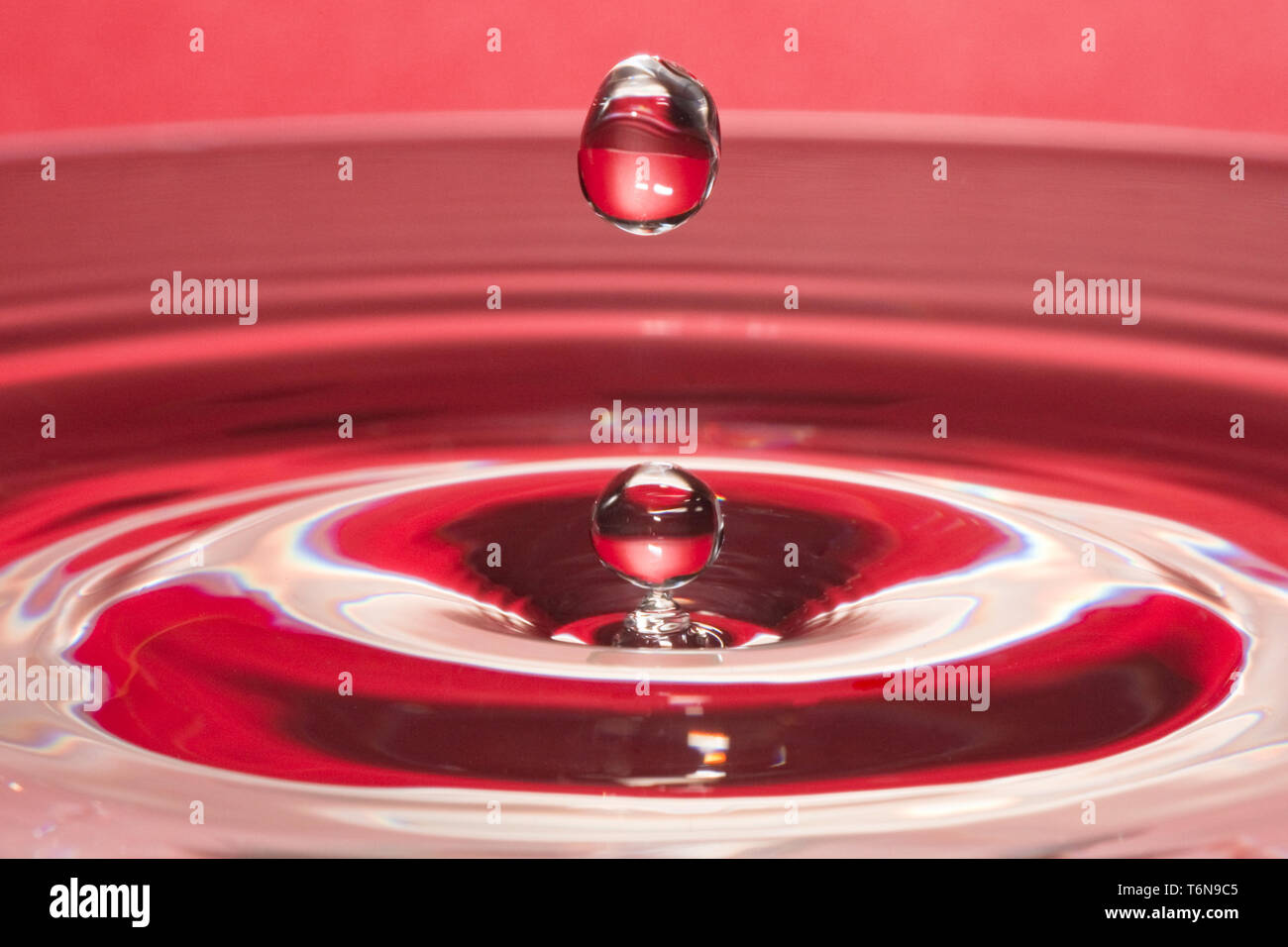 Closeup of falling water-drop in a red liquid Stock Photo - Alamy