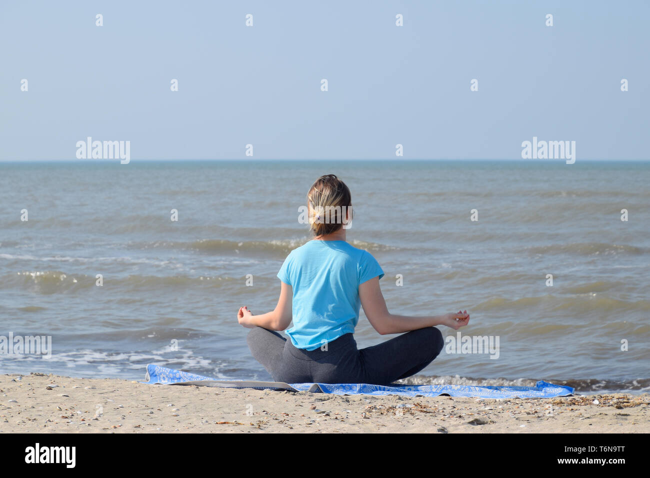 The girl practices yoga by the sea. Exercise gymnastics in the fresh ...