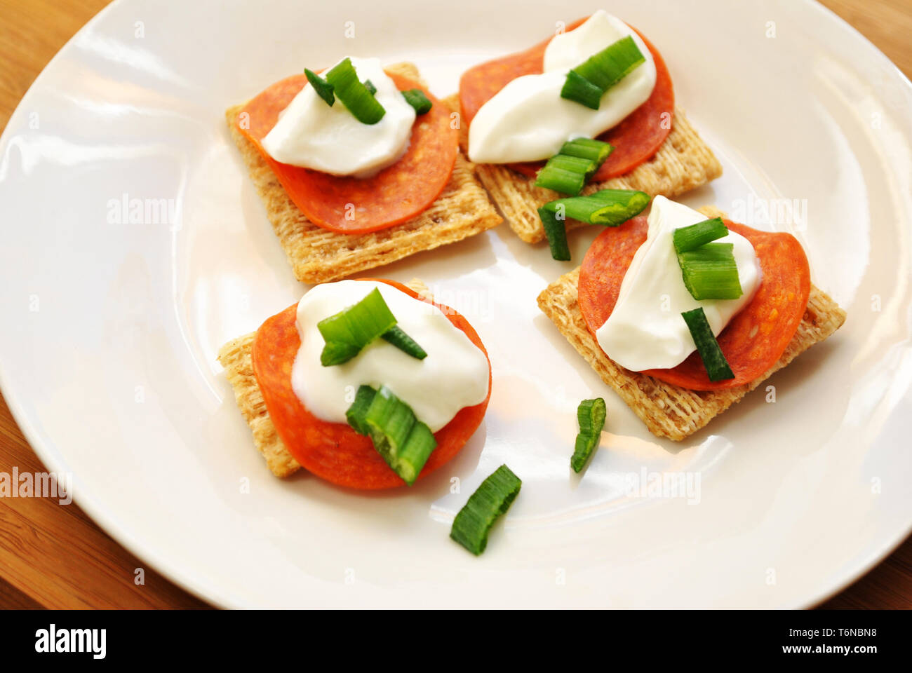 Appetizer of Wheat Crackers, Pepperoni, Sour Cream & Sliced Scallions ...