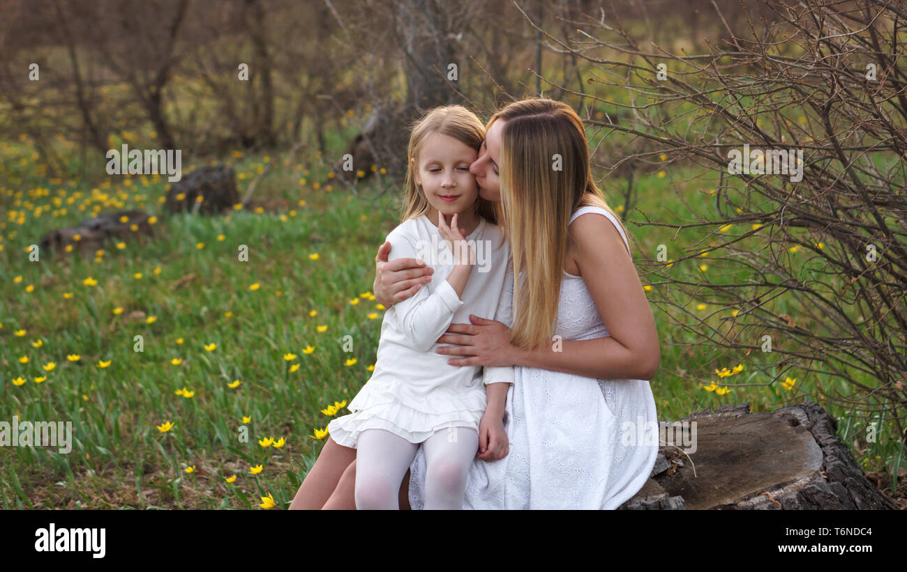 Attractive mother gently kisses her daughter on her lap. Family on a ...