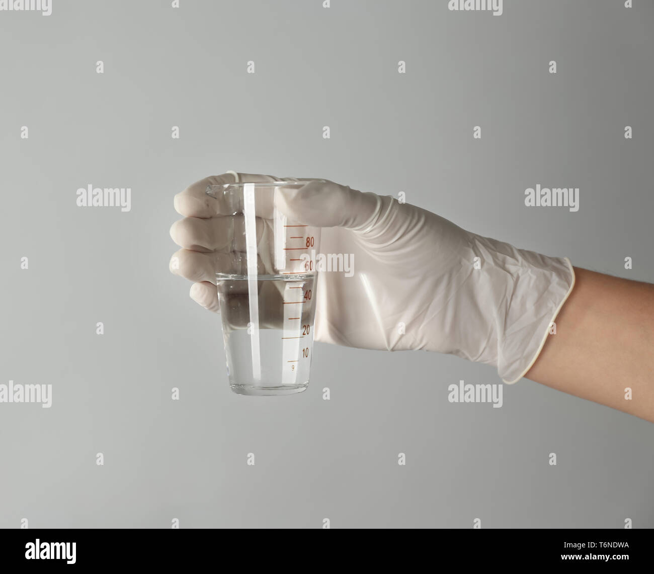 Laboratory worker holding beaker with water on grey background Stock ...