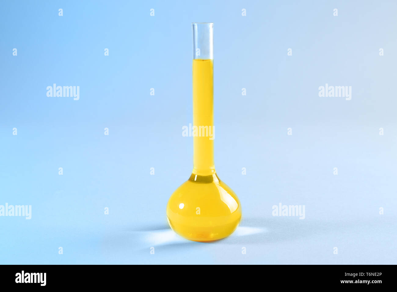 Test flask with yellow sample on color background Stock Photo - Alamy
