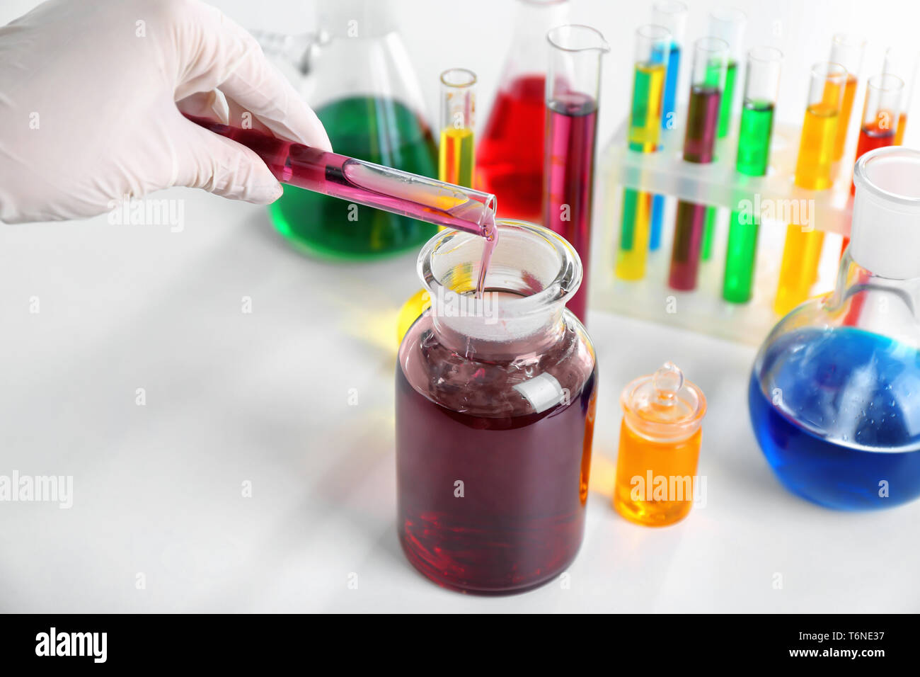 Hand in glove pouring sample into bottle, closeup Stock Photo - Alamy