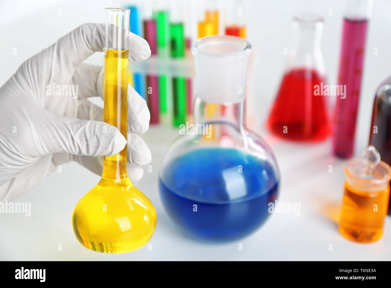 Scientist holding test flask with color sample in laboratory, closeup ...