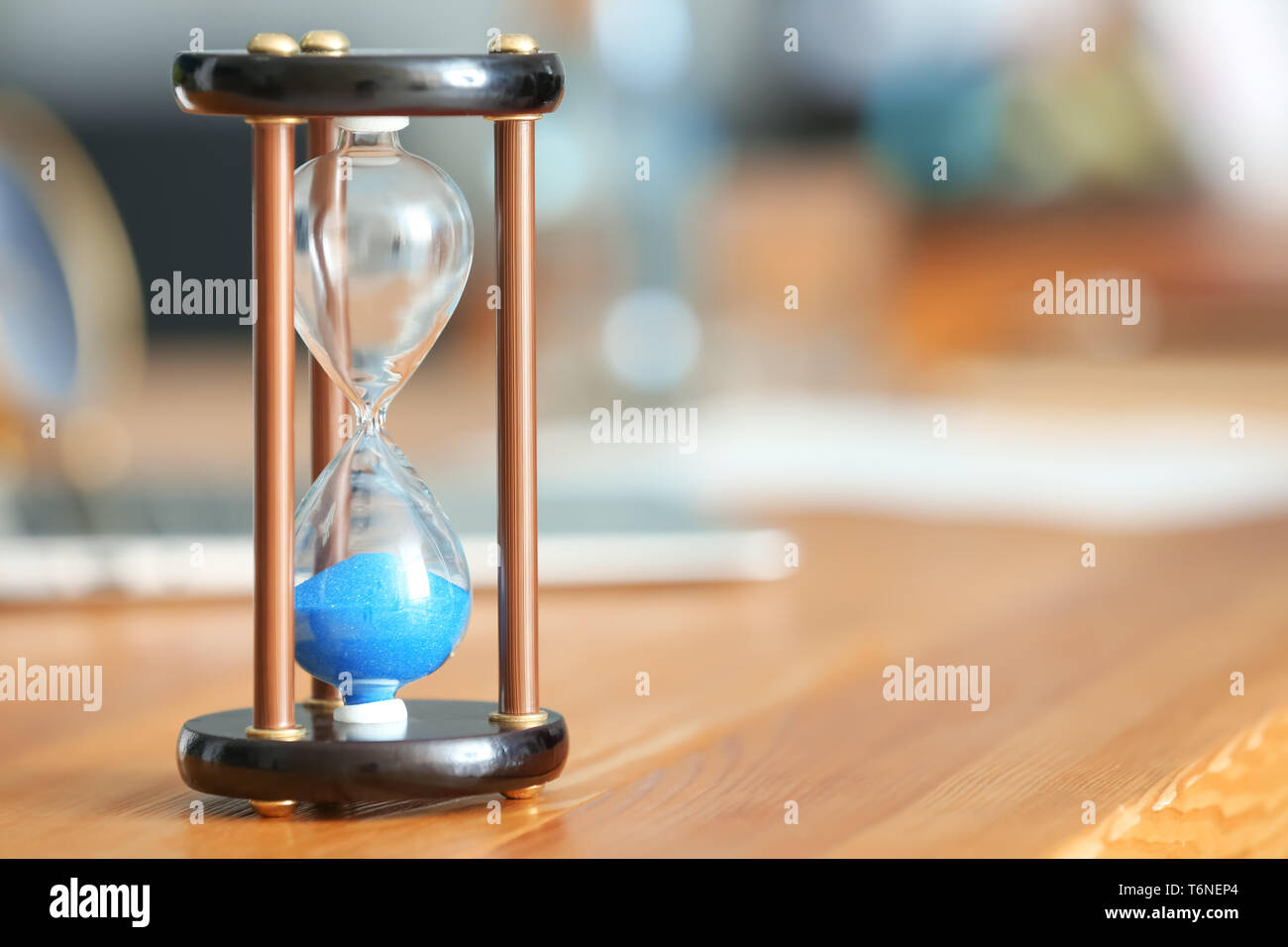 Hourglass on table against blurred background. Time management concept ...