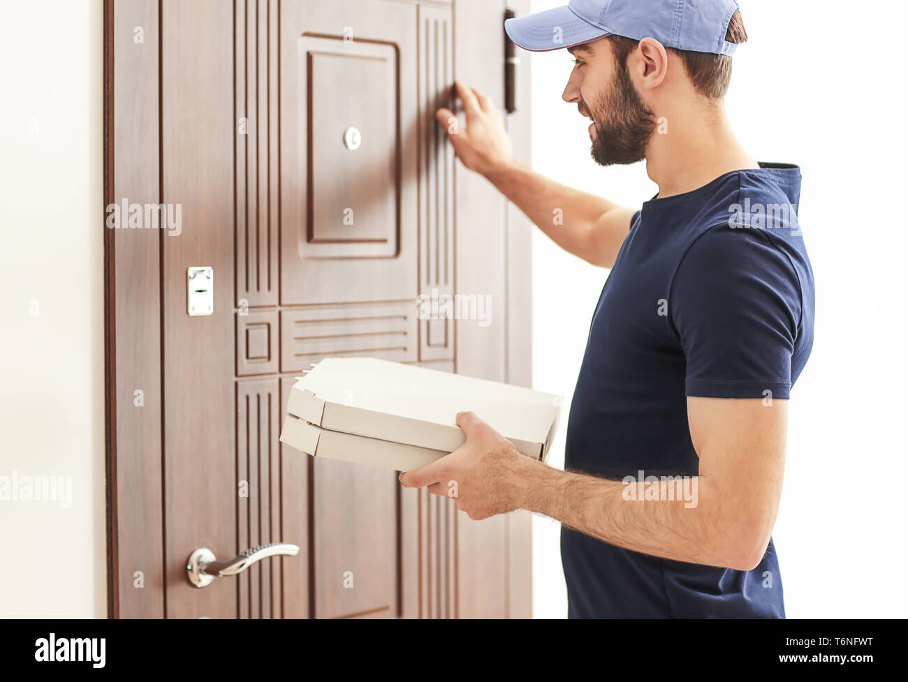 Delivery man with cardboard pizza boxes near door indoors Stock Photo ...