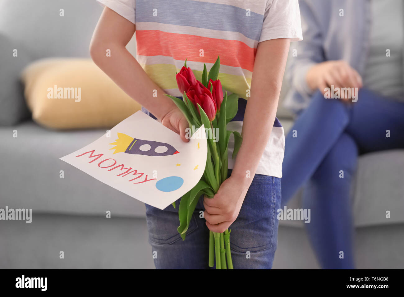 Little boy hiding gifts for mother behind his back at home Stock Photo ...