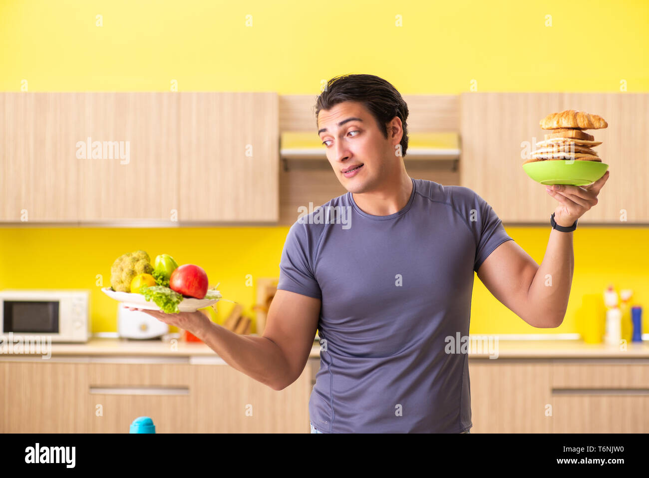 Man having hard choice between healthy and unhealthy food Stock Photo ...