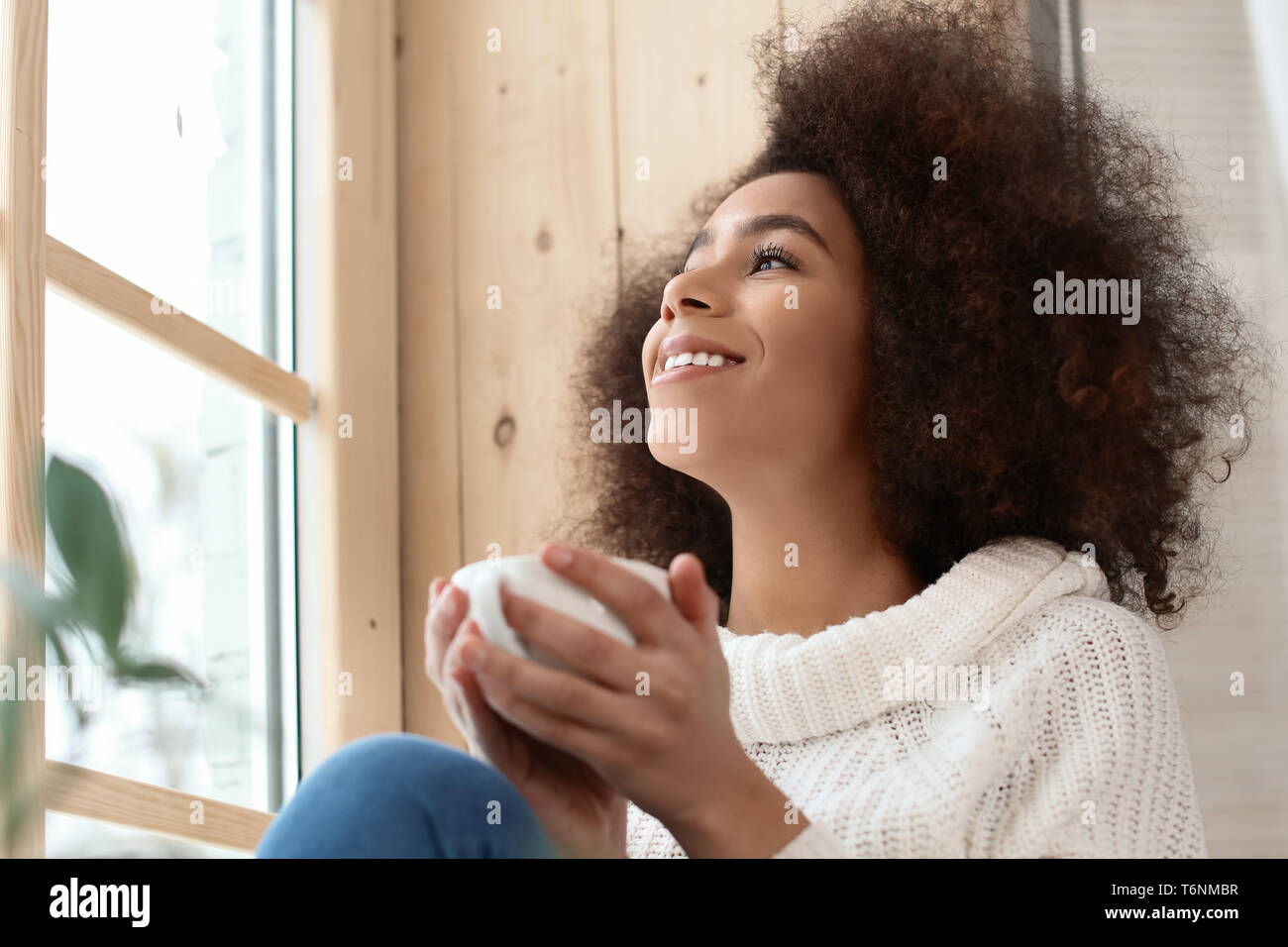 Beautiful African-American woman drinking tea near window Stock Photo ...