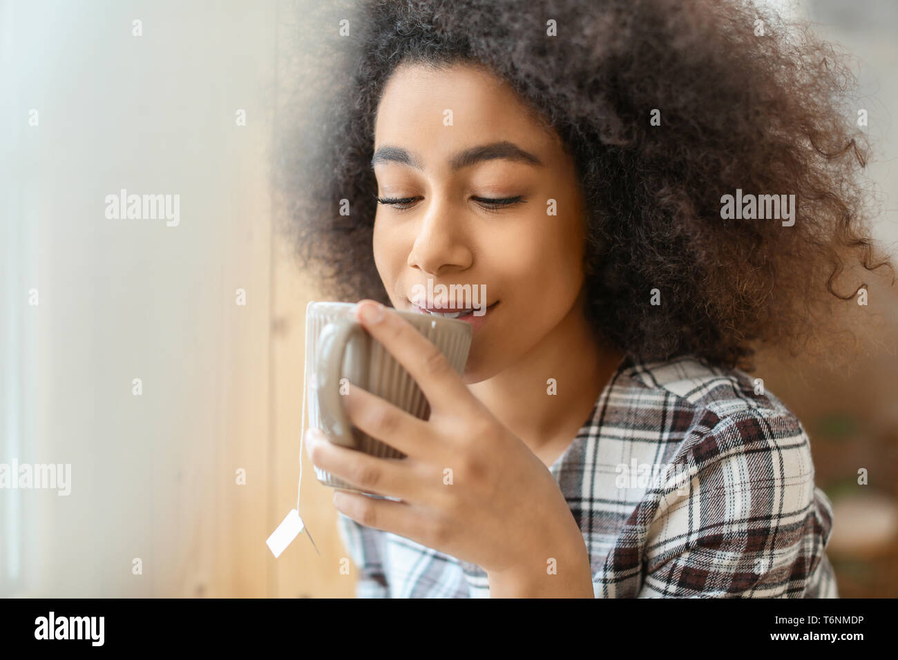 Beautiful African-American woman drinking tea indoors Stock Photo - Alamy