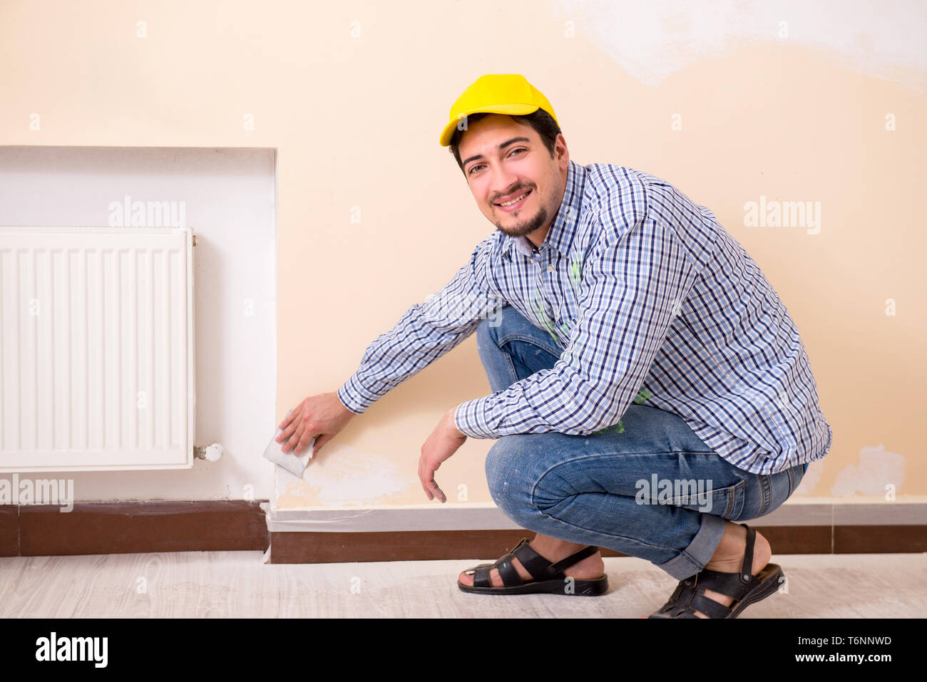 The young contractor sanding wall down with sandpaper Stock Photo - Alamy