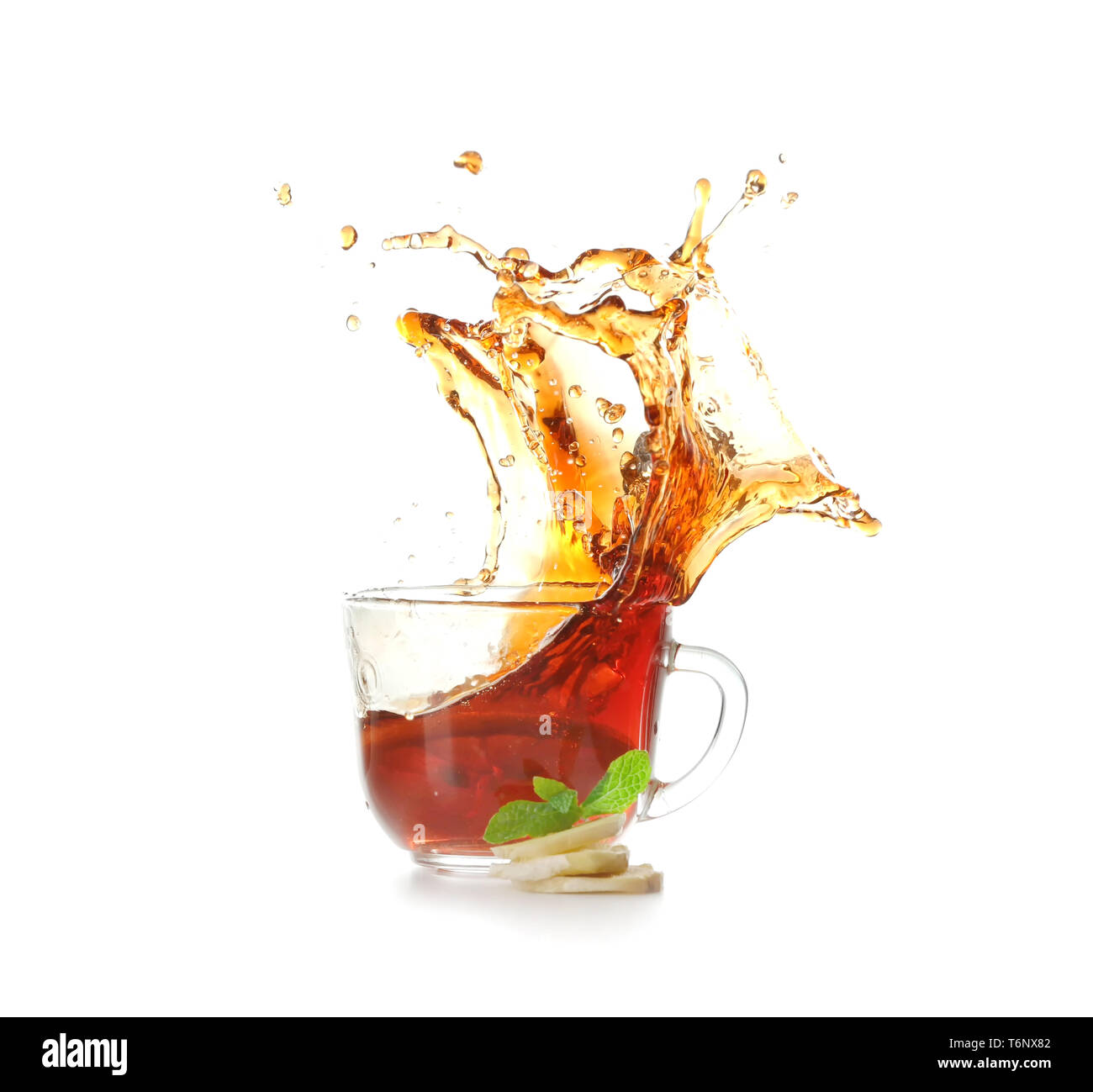 Glass cup and splash of delicious lemon tea with ginger on white ...