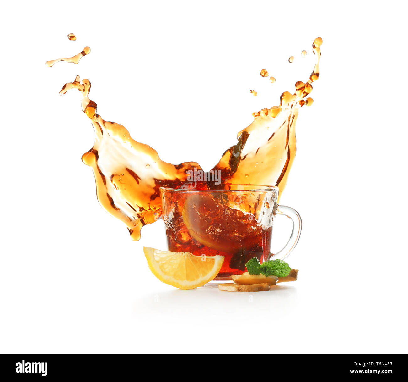 Glass cup and splash of delicious lemon tea with ginger on white ...