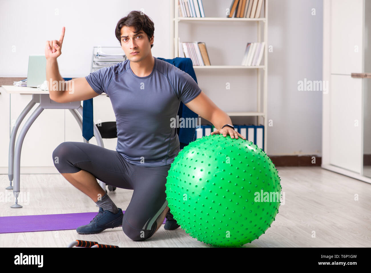 Young male employee exercising in the office Stock Photo - Alamy