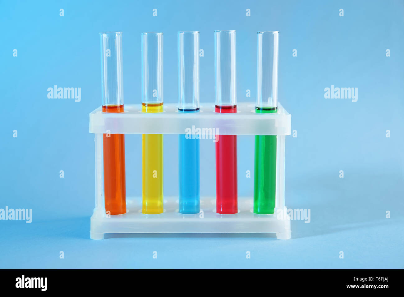 Test tubes with colorful liquids in holder on color background Stock ...