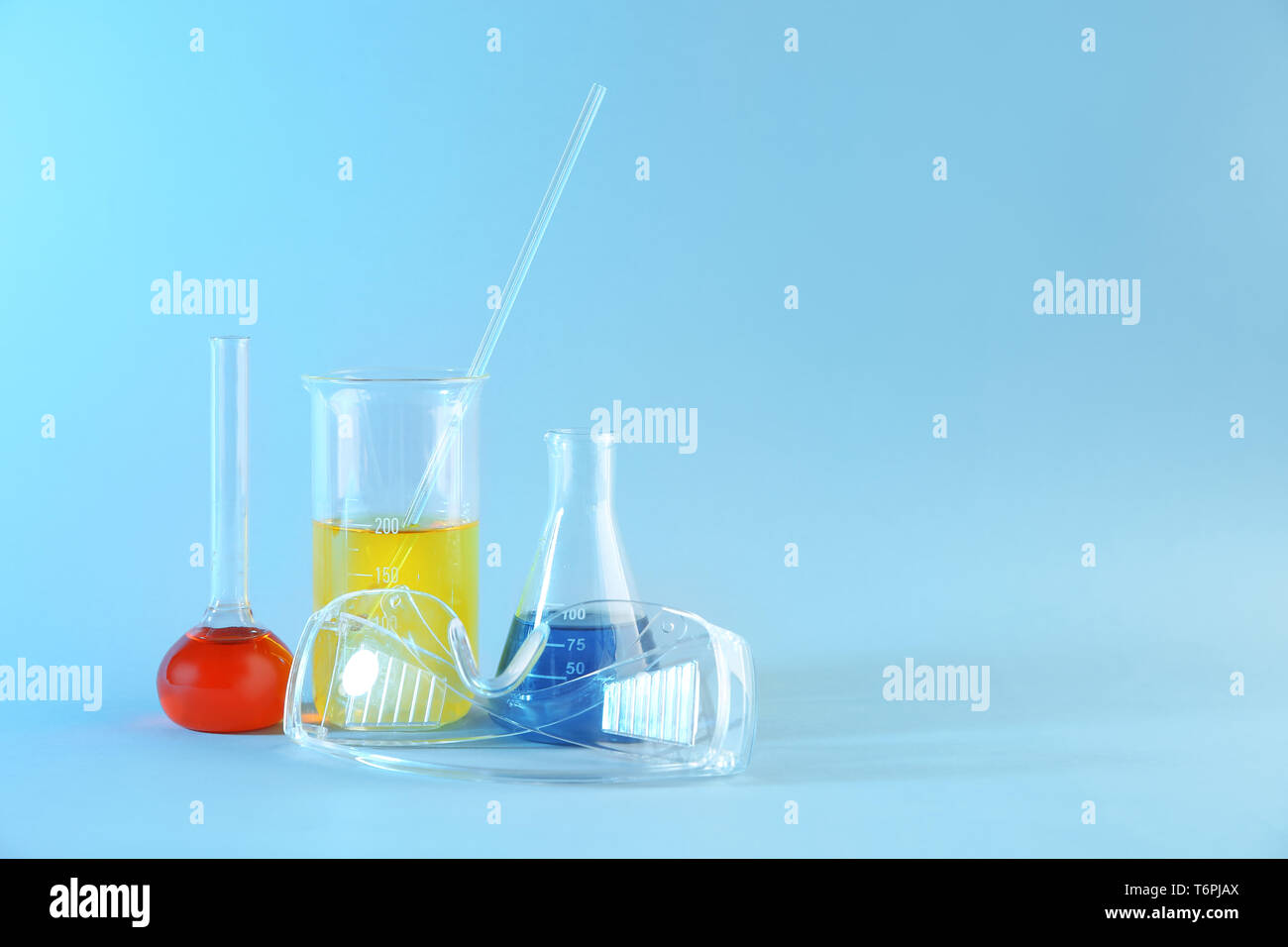 Chemical glassware with colorful samples and lab goggles on color ...