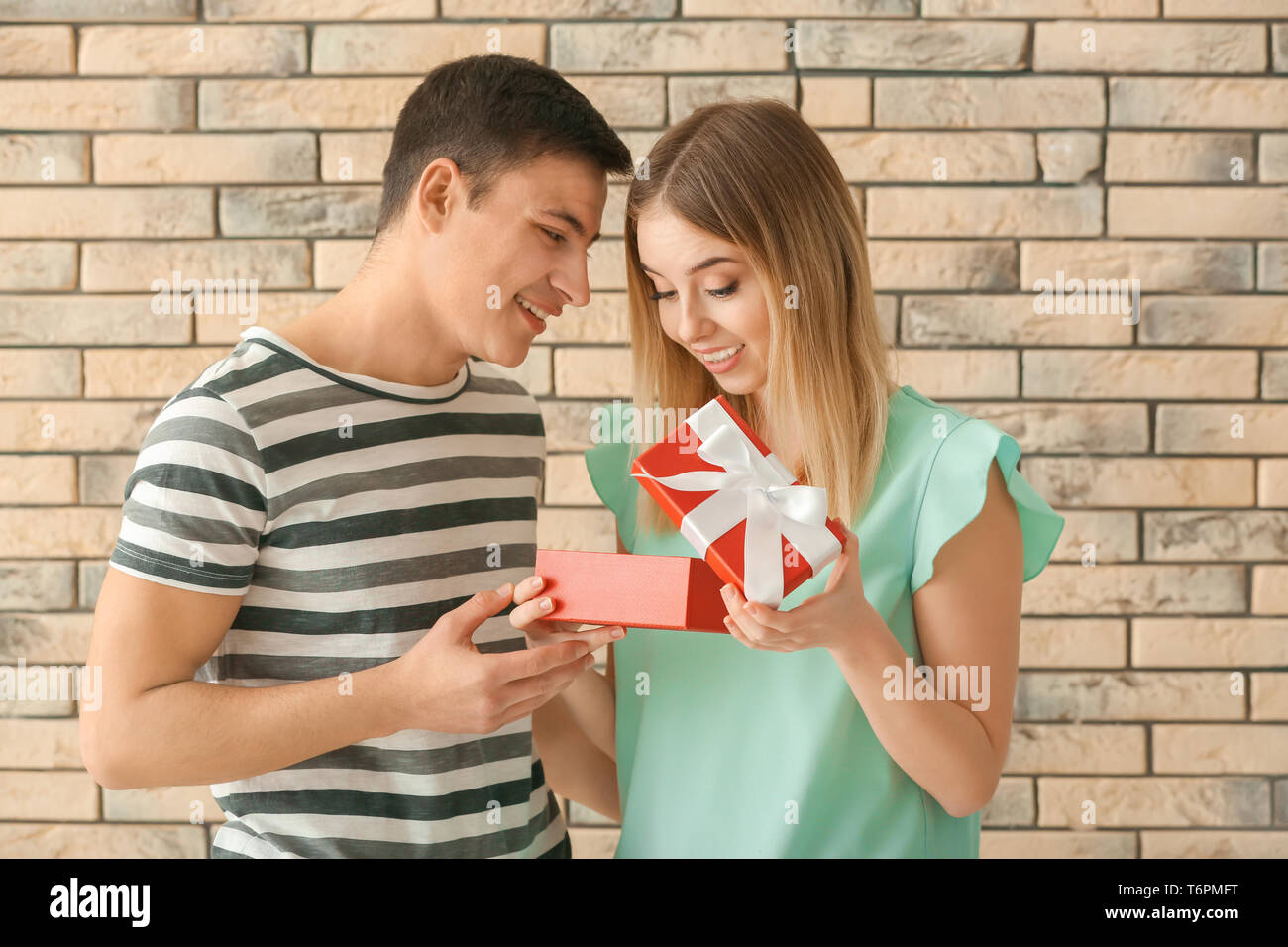 Young woman opening gift box from her boyfriend near brick wall Stock ...