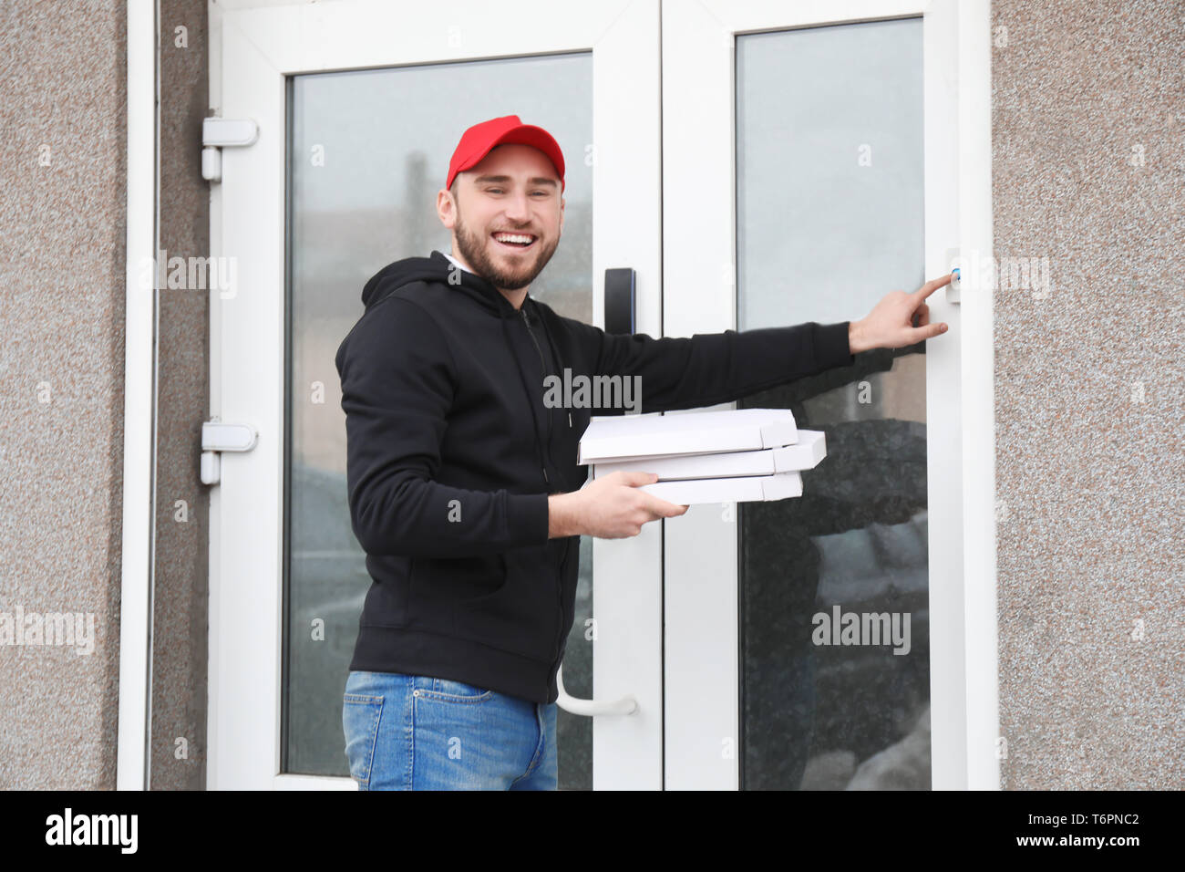 Young man with cardboard pizza boxes ringing doorbell outdoors. Food ...