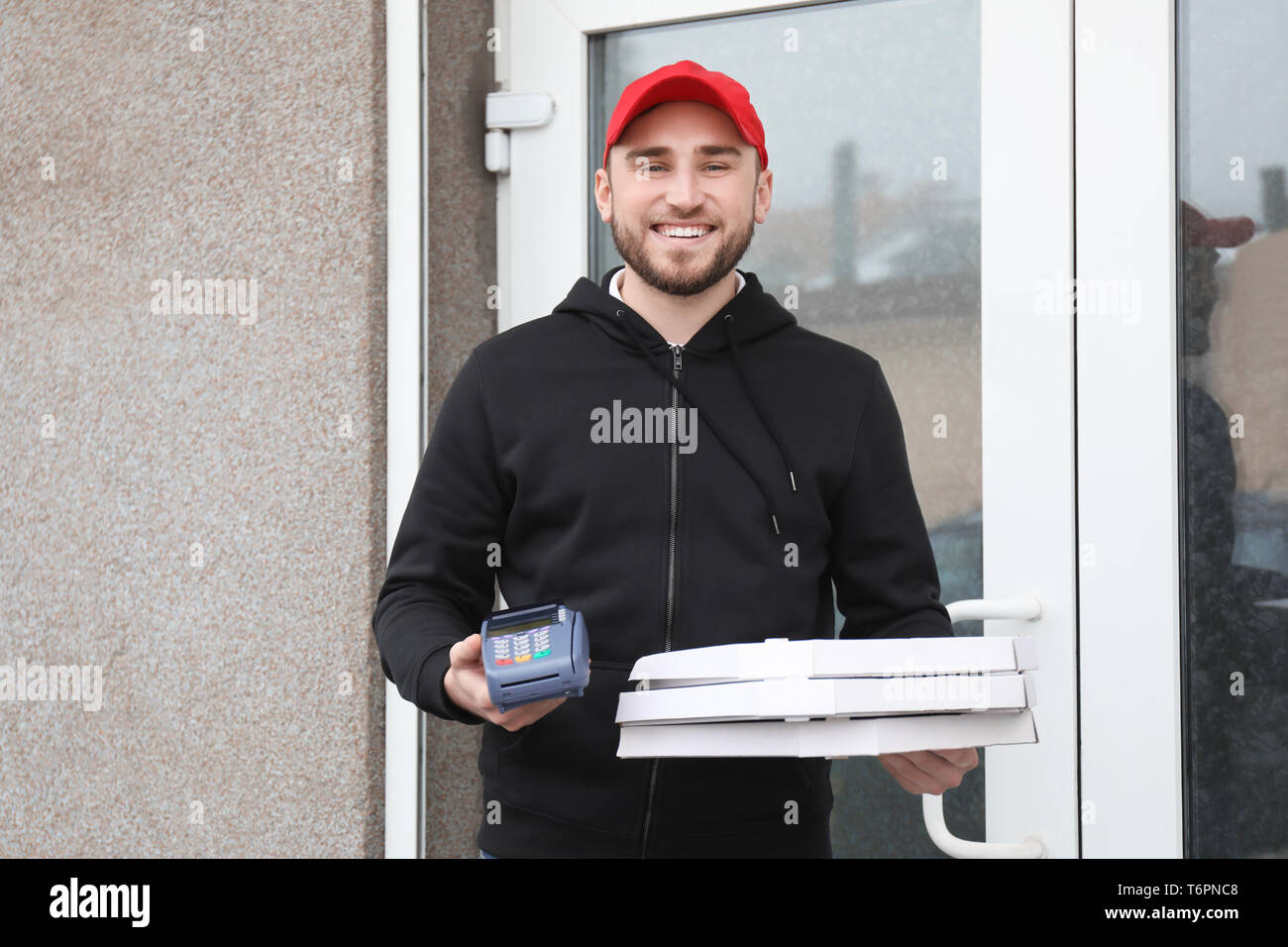 Young man with cardboard pizza boxes and bank terminal outdoors. Food ...