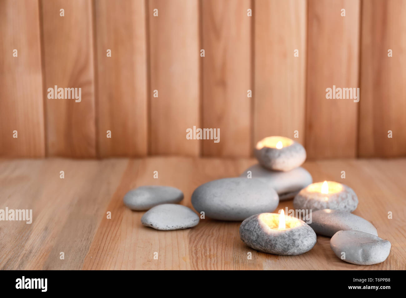 Burning candles with stones on wooden background Stock Photo - Alamy