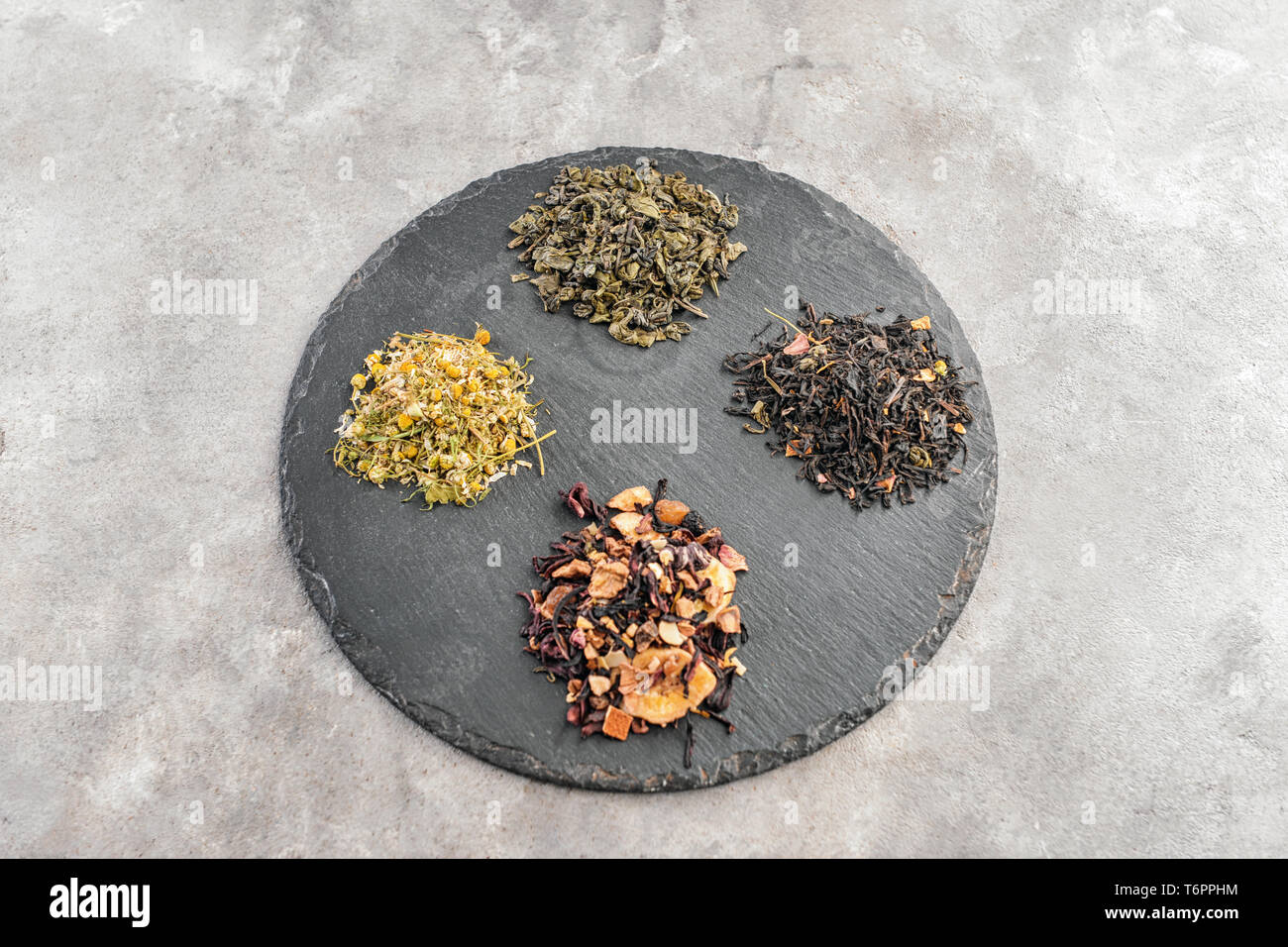 Slate plate with different types of dry tea on grey background Stock ...