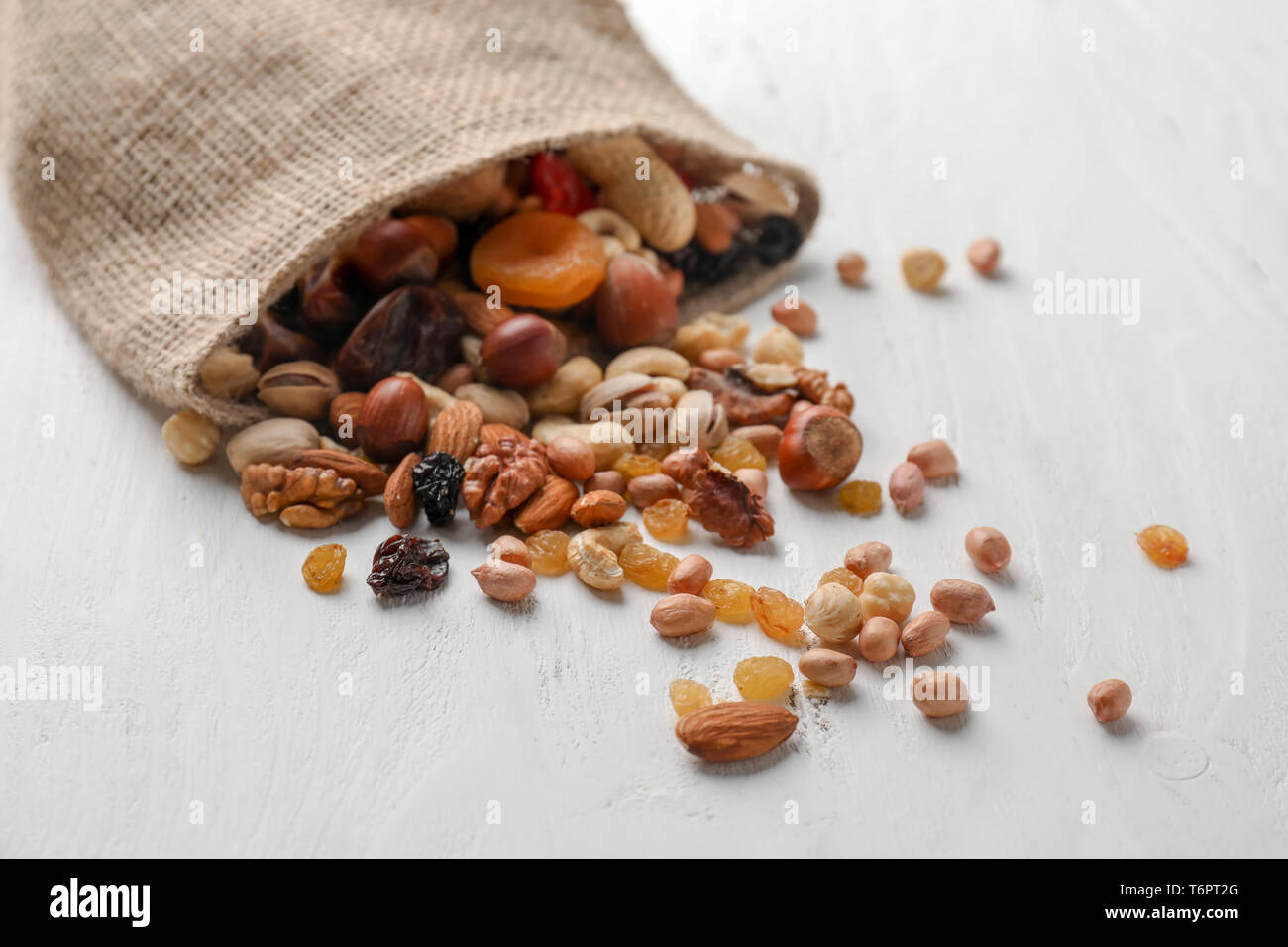 Sackcloth bag with mix of nuts and dried fruits on light background ...