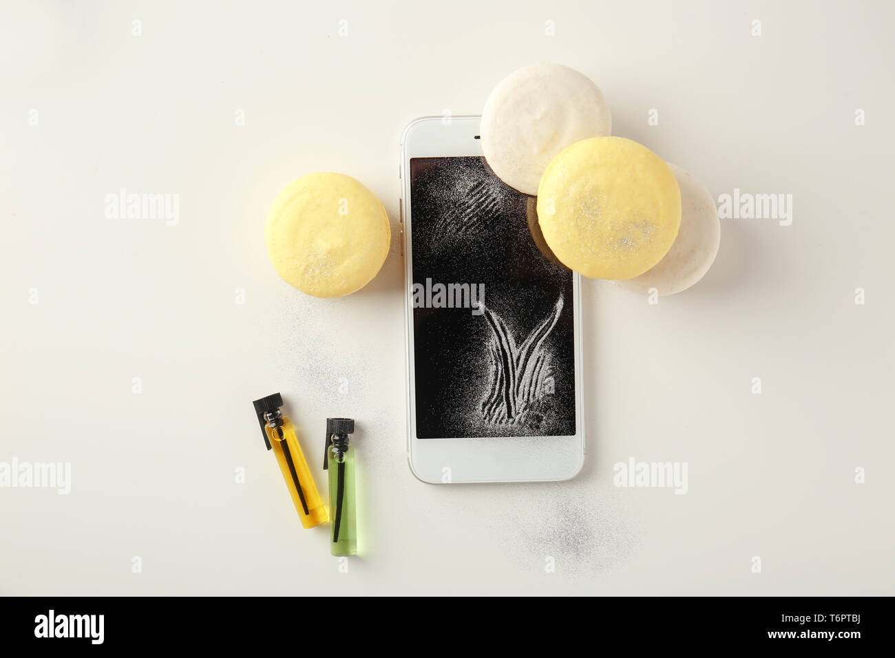Tasty macarons with phone on white background Stock Photo - Alamy