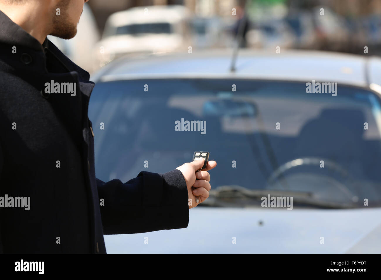 Man pushing button on remote control of car alarm system, outdoors ...