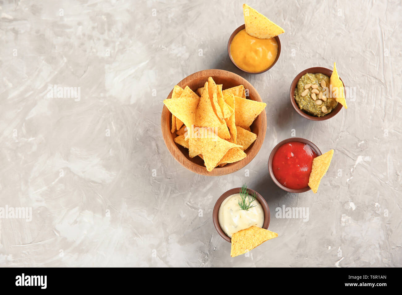 Composition with different sauces and nachos on grey textured ...