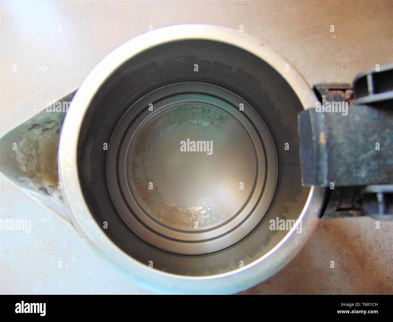 Limescale in kettle on the gray surface. Dirtykettle on the gray ...