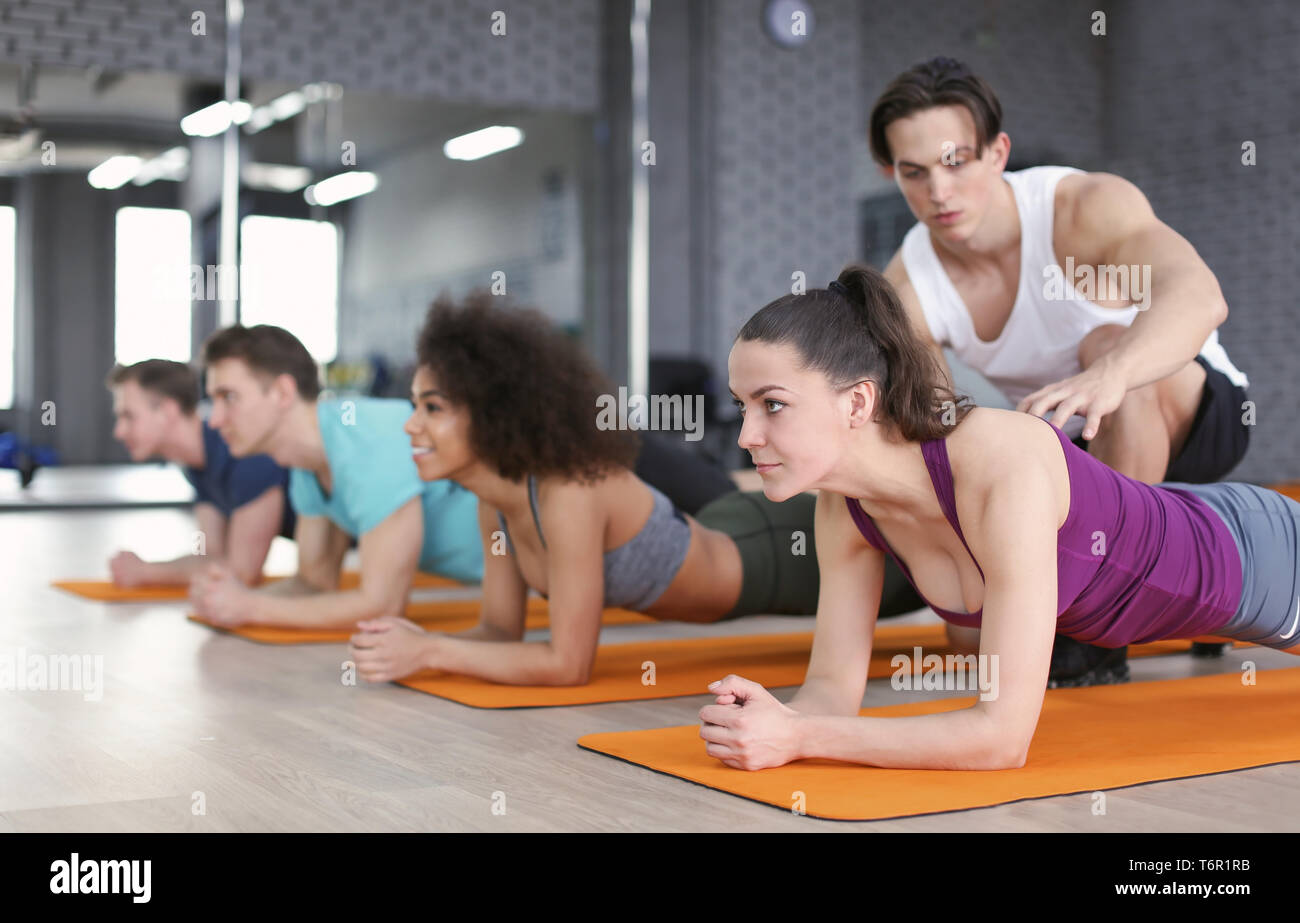 Sporty young people doing exercise in gym Stock Photo - Alamy