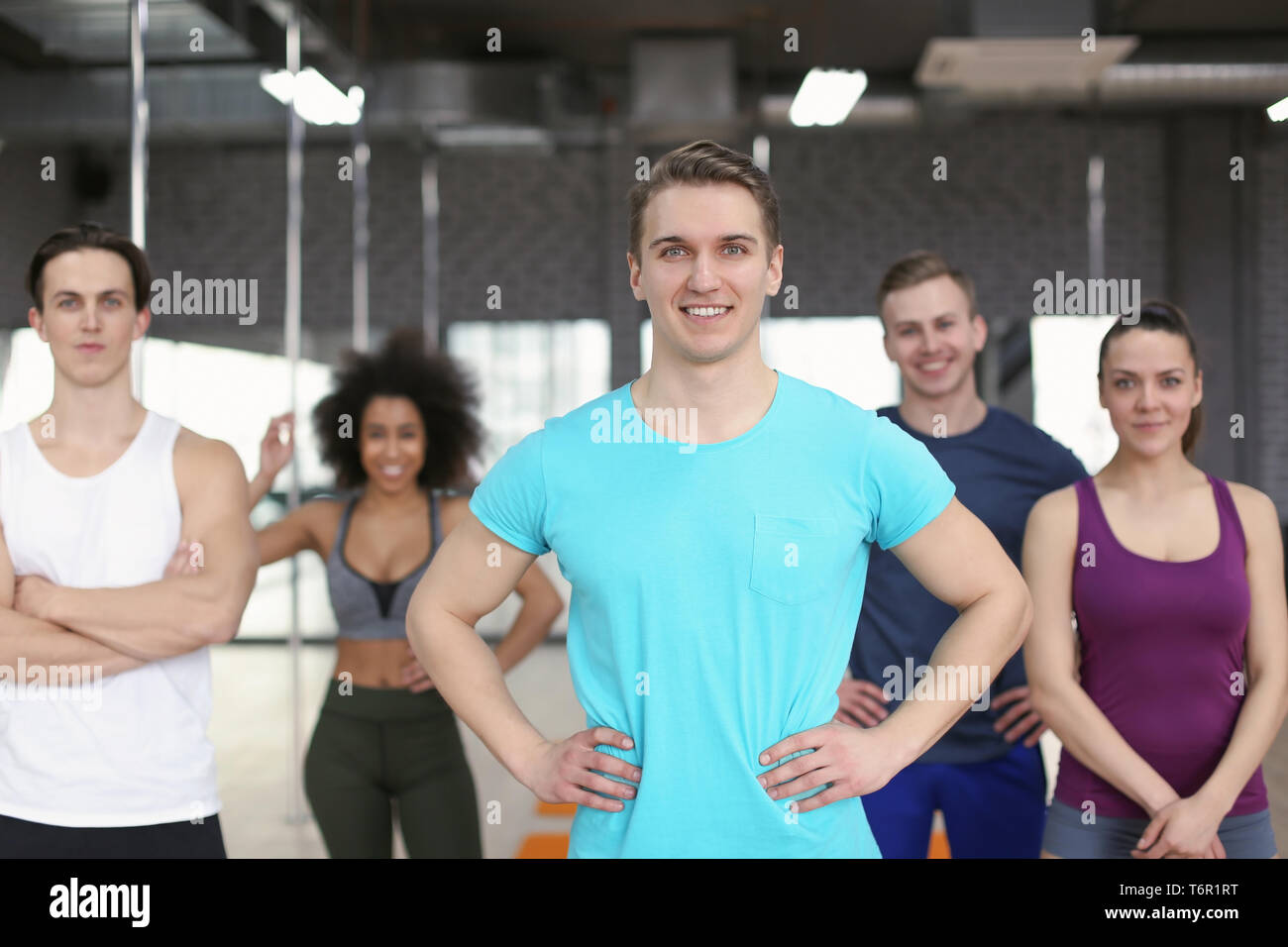 Sporty man with group of athletes in gym Stock Photo - Alamy