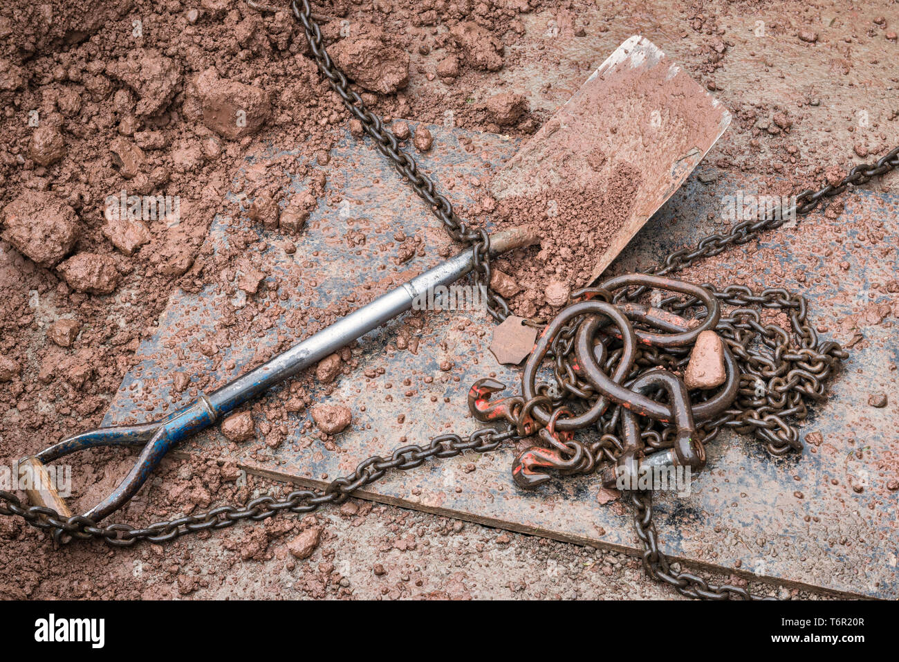 A builders' spade, heavy metal chains, rain and mud. Still life on a ...