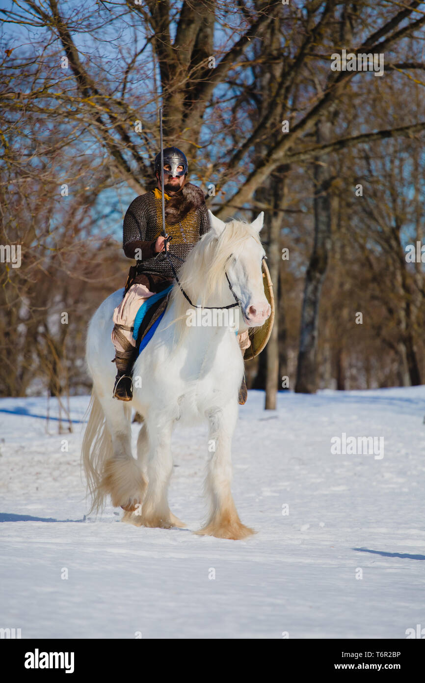 Man in suit of ancient warrior riding big white horse Stock Photo - Alamy