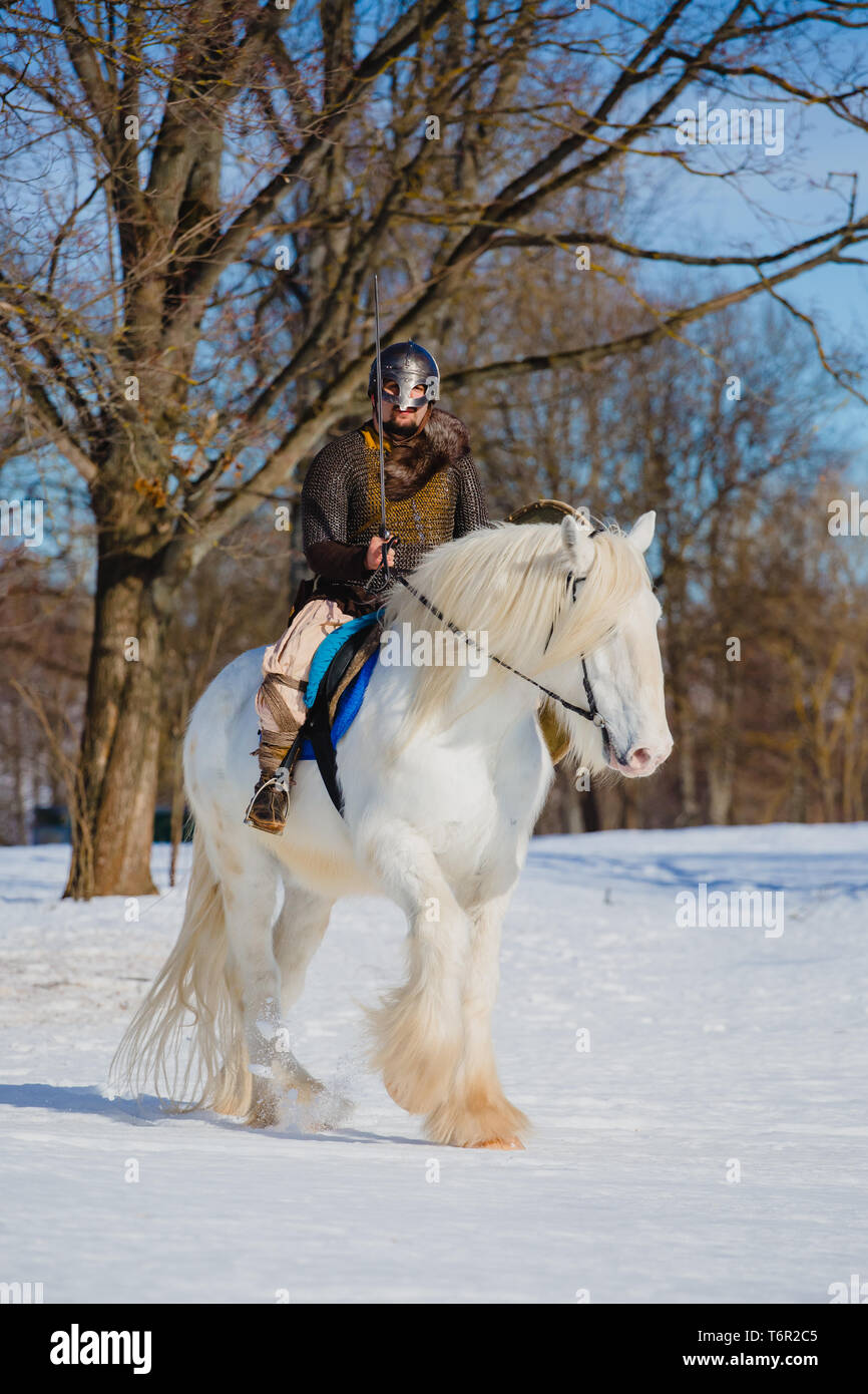 Man in suit of ancient warrior riding big white horse Stock Photo - Alamy