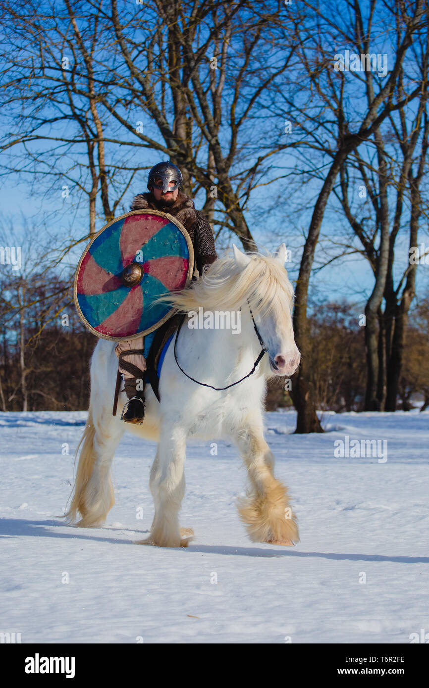 Man in suit of ancient warrior riding big white horse Stock Photo - Alamy