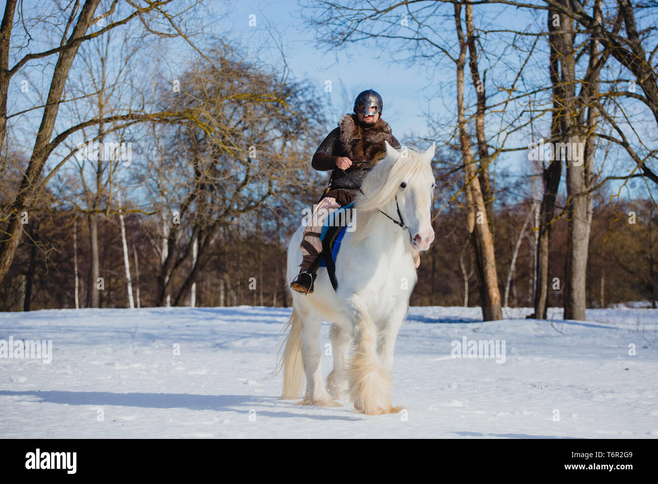 Man in suit of ancient warrior riding big white horse Stock Photo - Alamy