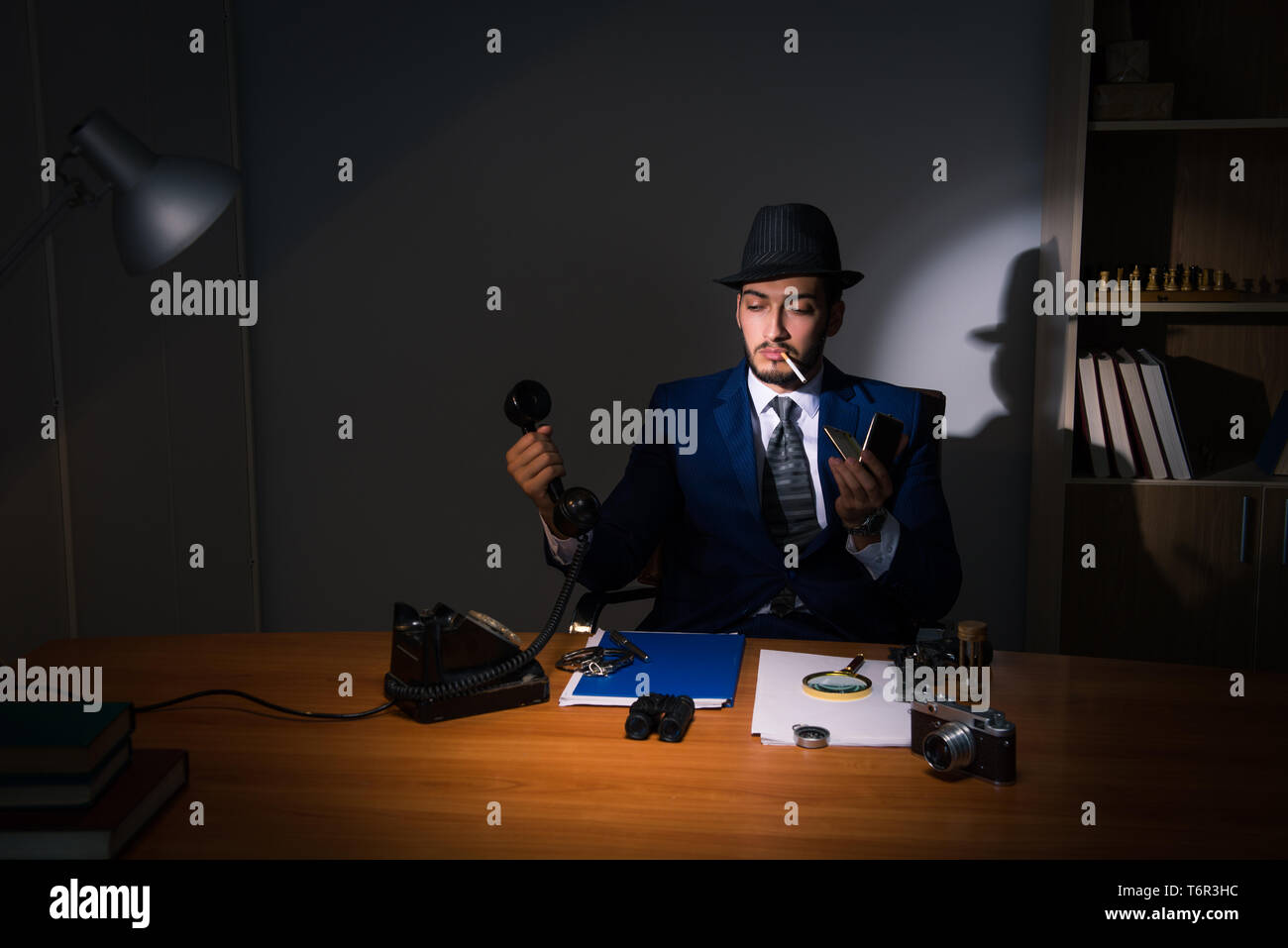 Detective sitting in dark room in vintage concept Stock Photo - Alamy