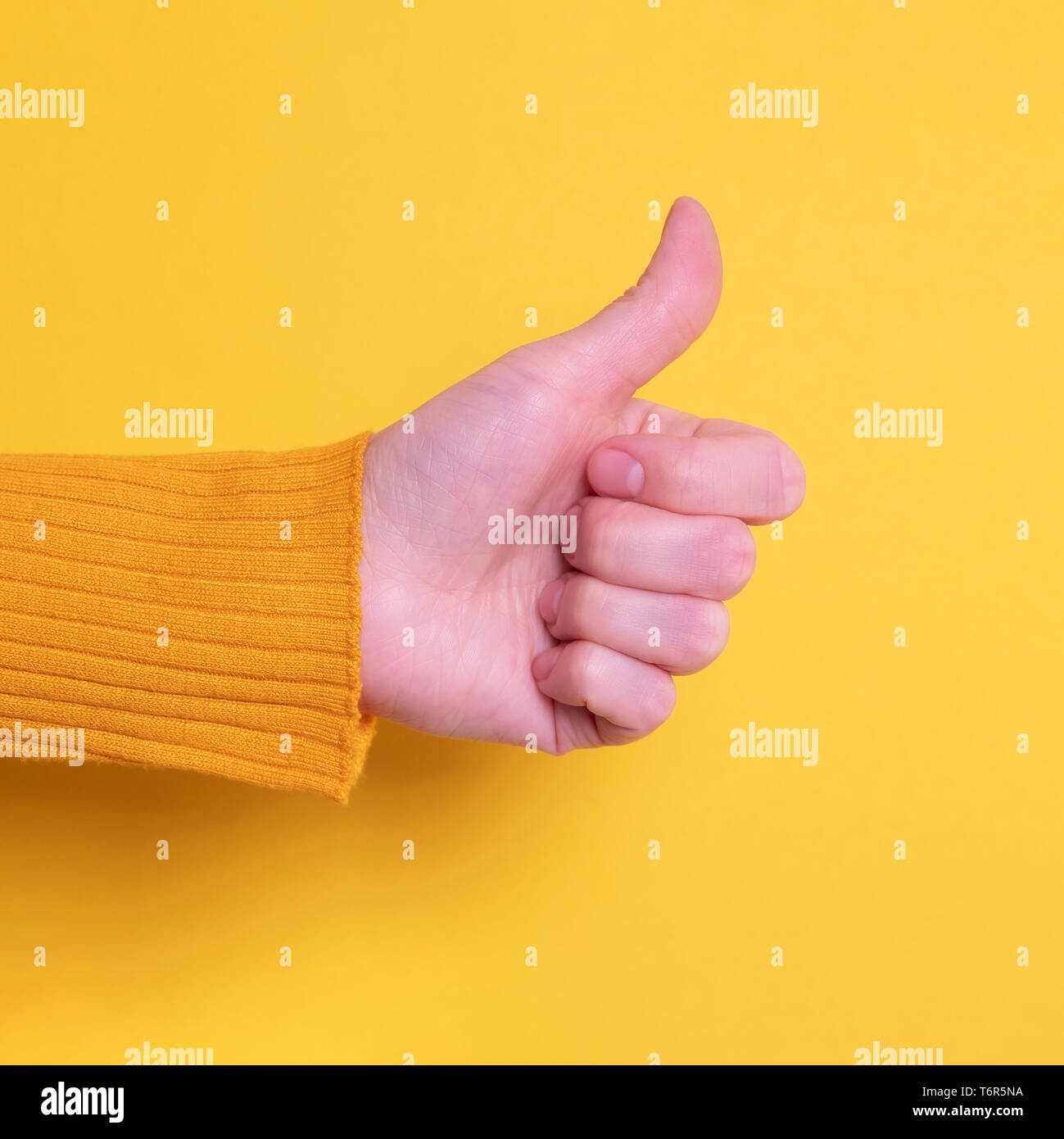 Beautiful woman hand making thumb up gesture on yellow bright ...
