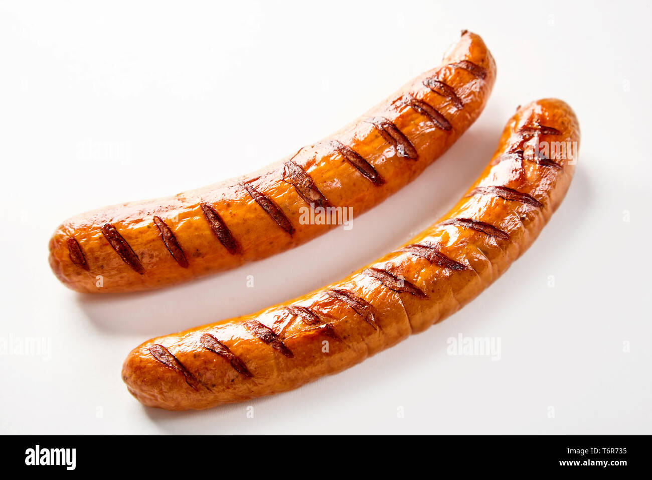 Two seared barbecue sausages on a white background with copy space ...