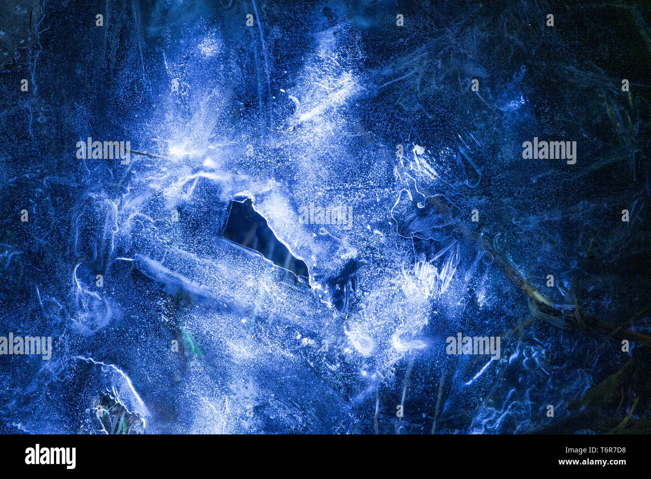 Network of cracks in thick solid frozen layer of ice with shining light ...