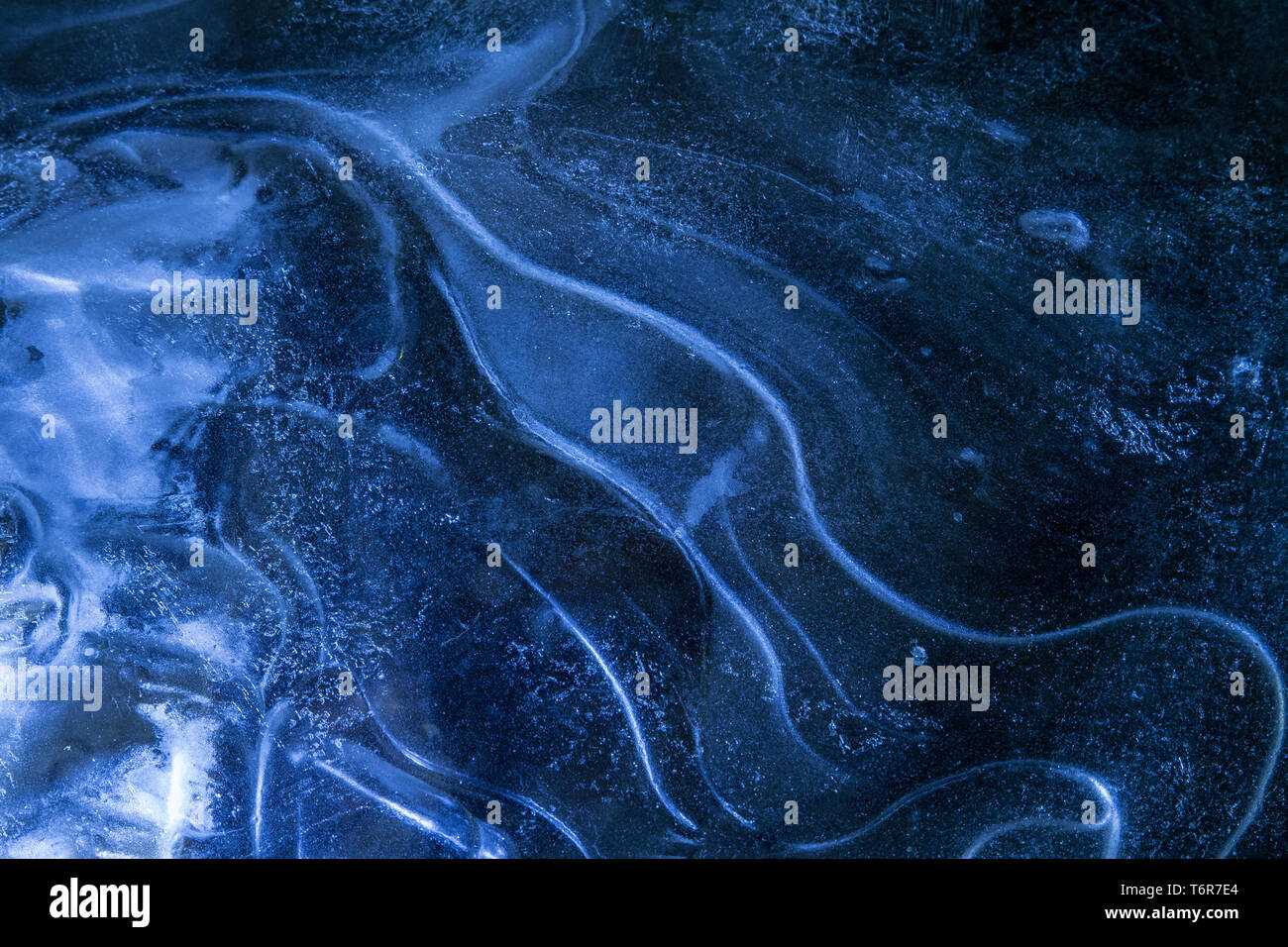 Network of cracks in thick solid frozen layer of ice with shining light ...