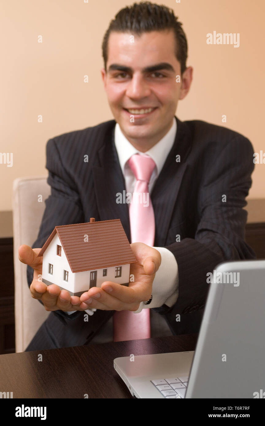 real estate concept with businessman and mini house Stock Photo - Alamy