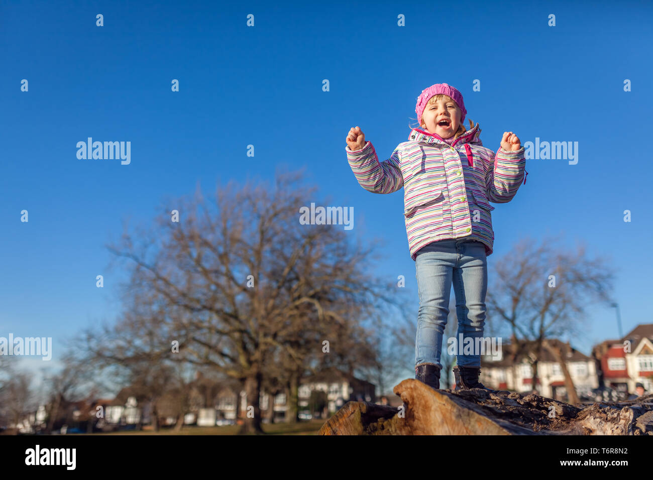 Happy girl on a large tree log Stock Photo - Alamy