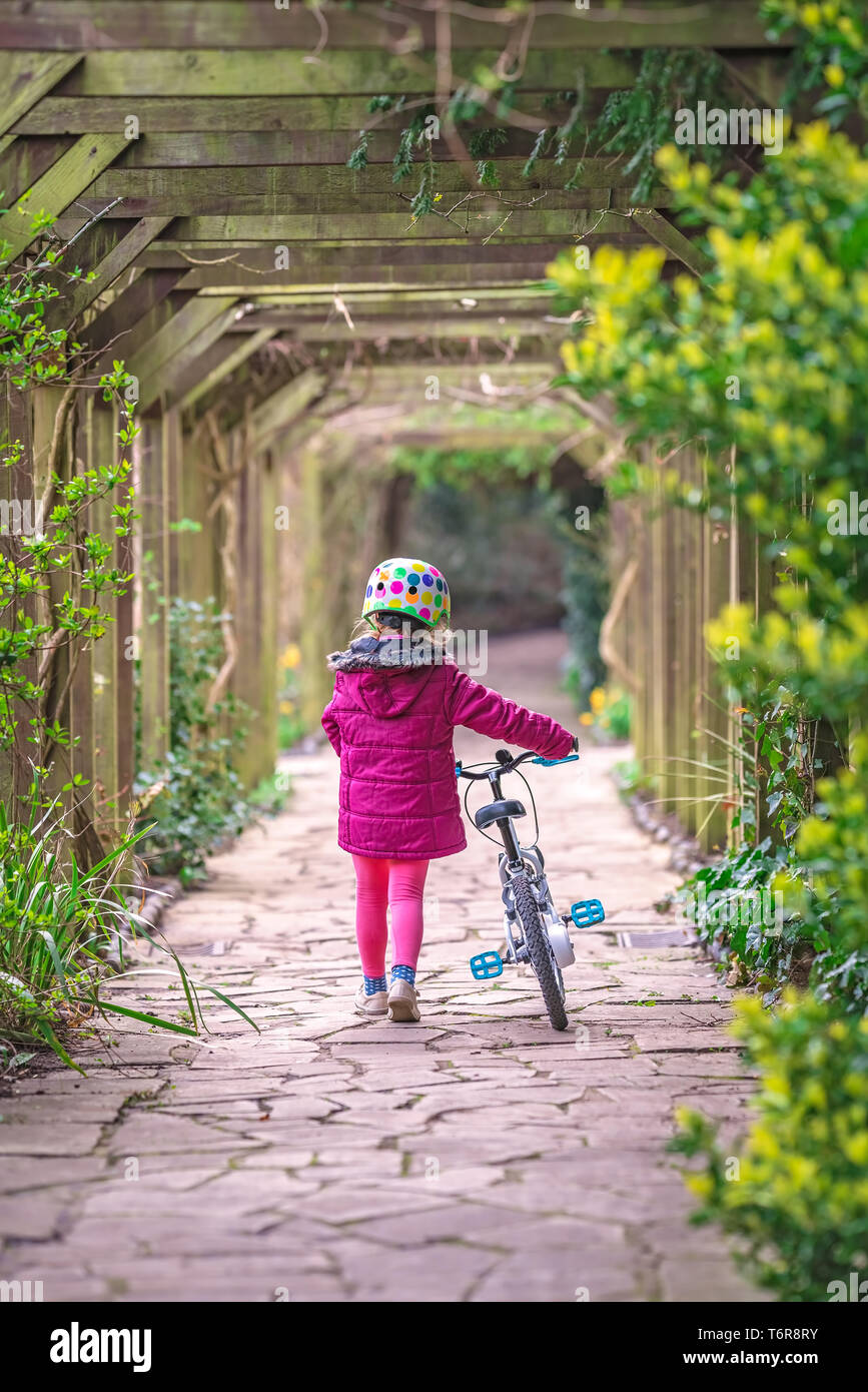 Young little girl pushing her bicycle Stock Photo - Alamy
