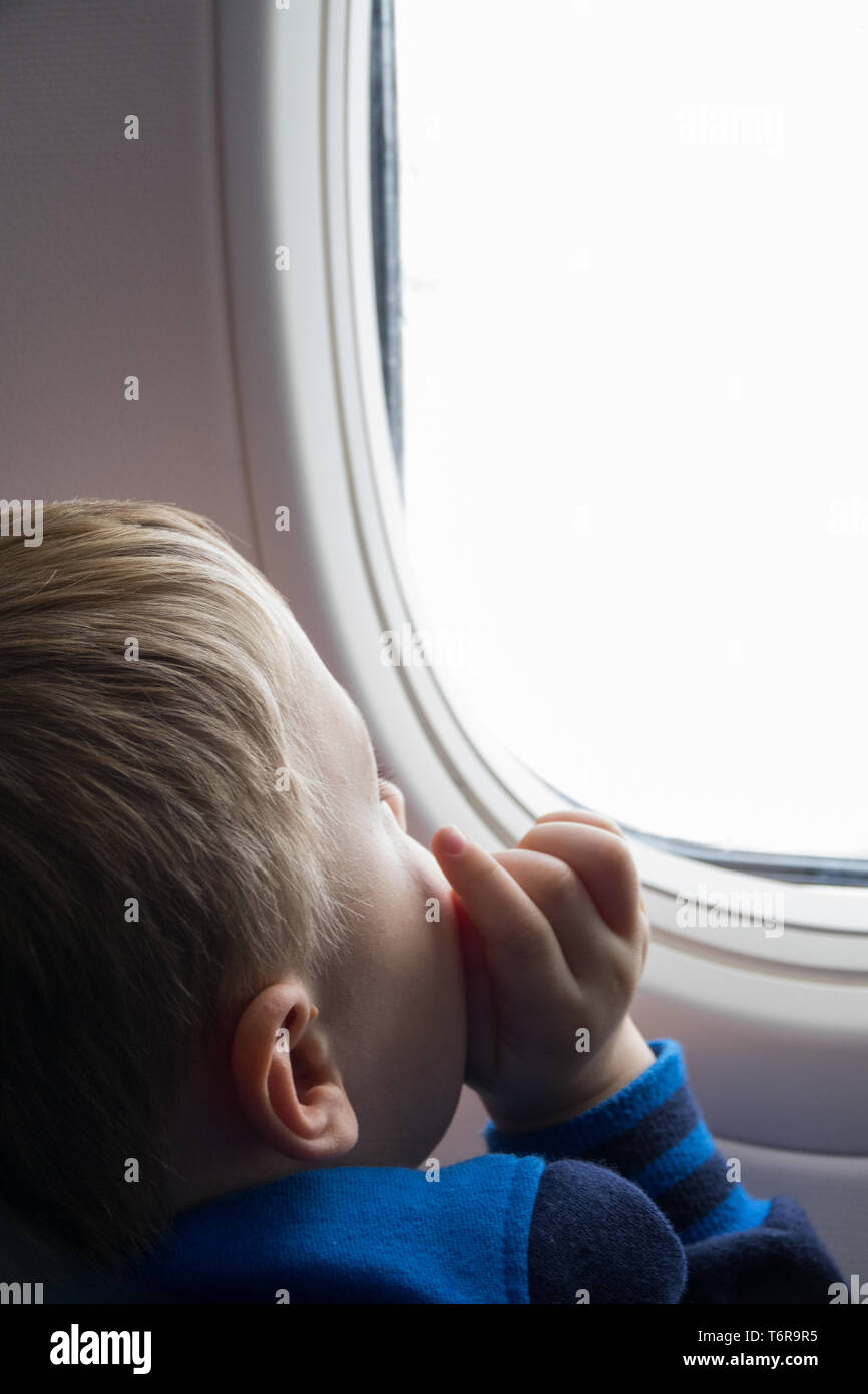 Little boy looking through the plane window Stock Photo - Alamy