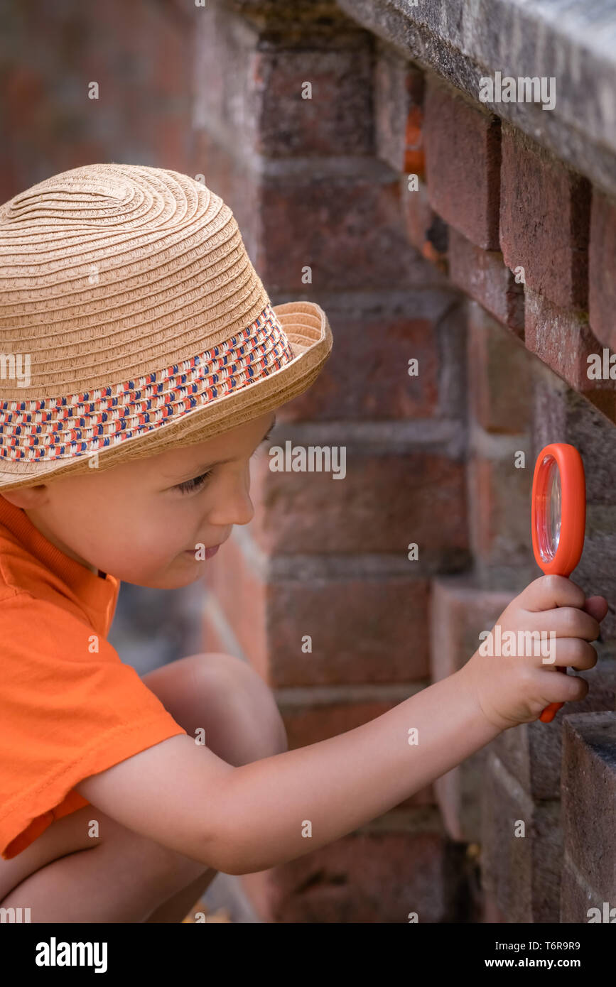 Little boy with magnifying glass looking for clues Stock Photo - Alamy