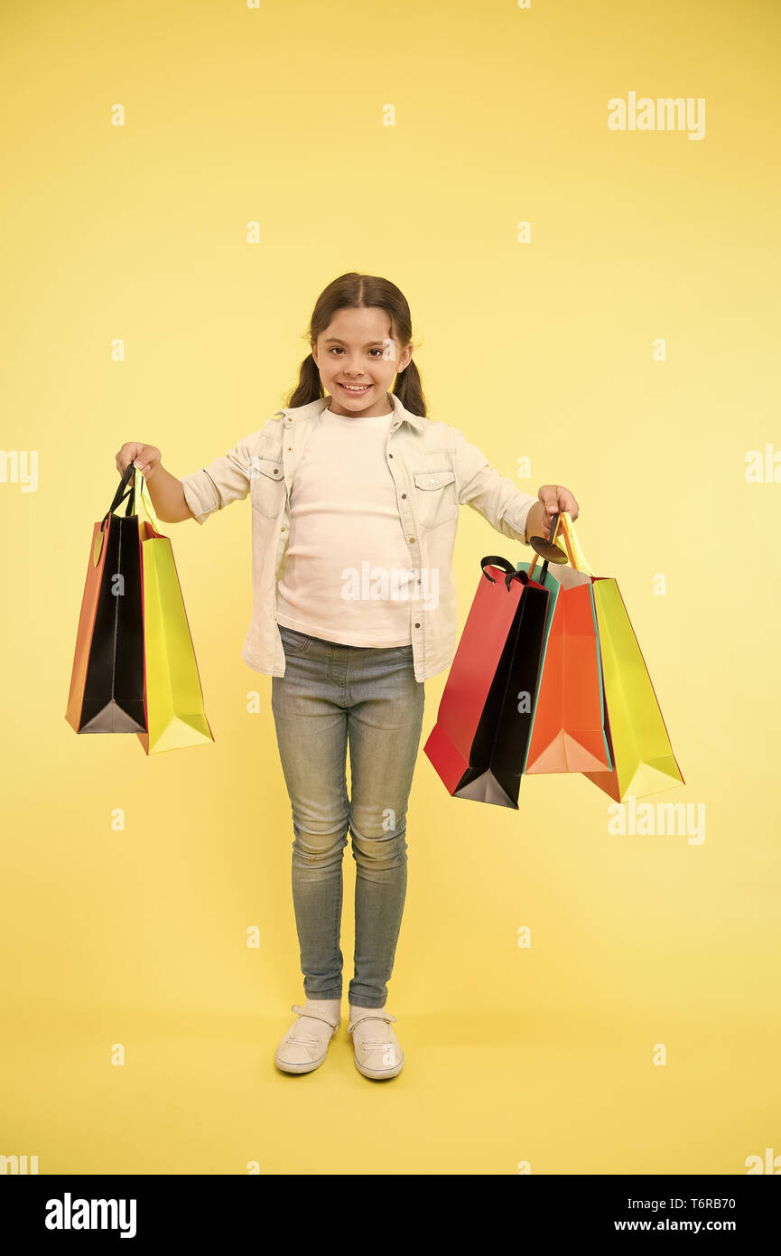 Little helper. Child cute fashionista helps carry packages during ...