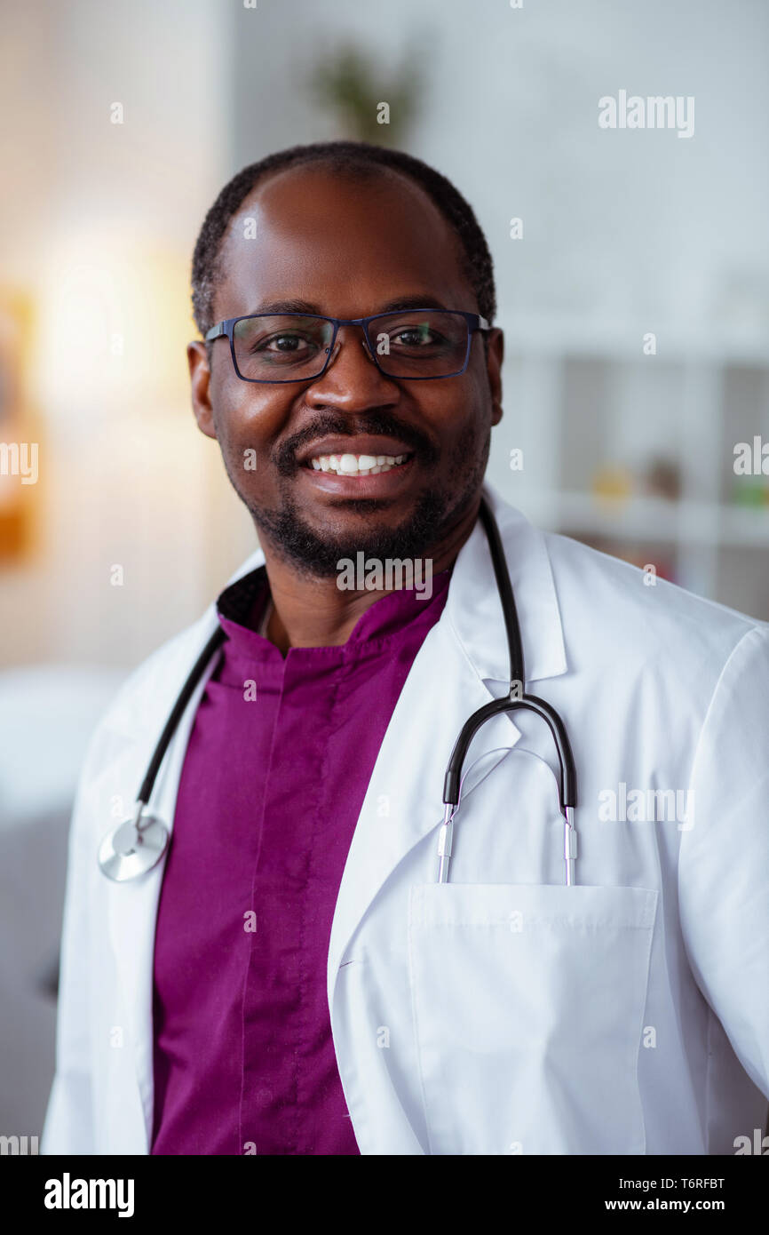 Handsome dark-skinned doctor smiling after good day at work Stock Photo ...