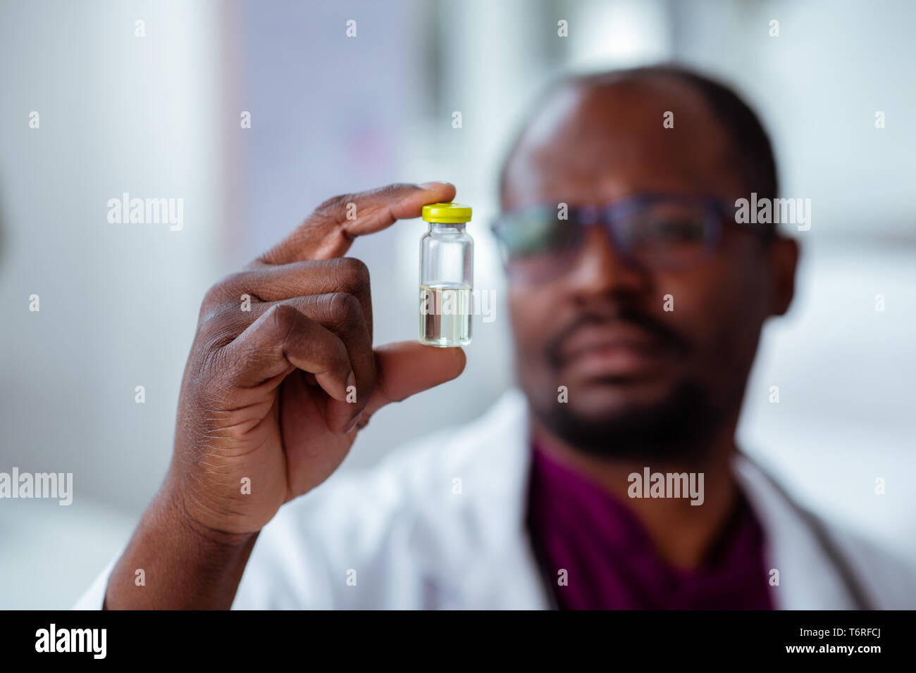 Dark-skinned doctor holding little ampoule with medicine Stock Photo ...